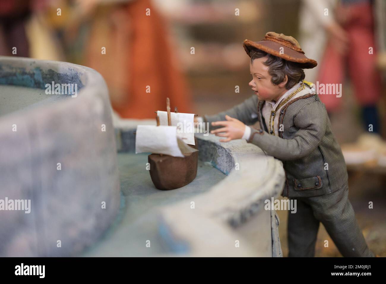 A figure representing a scene of a boy playing with a boat in a ...