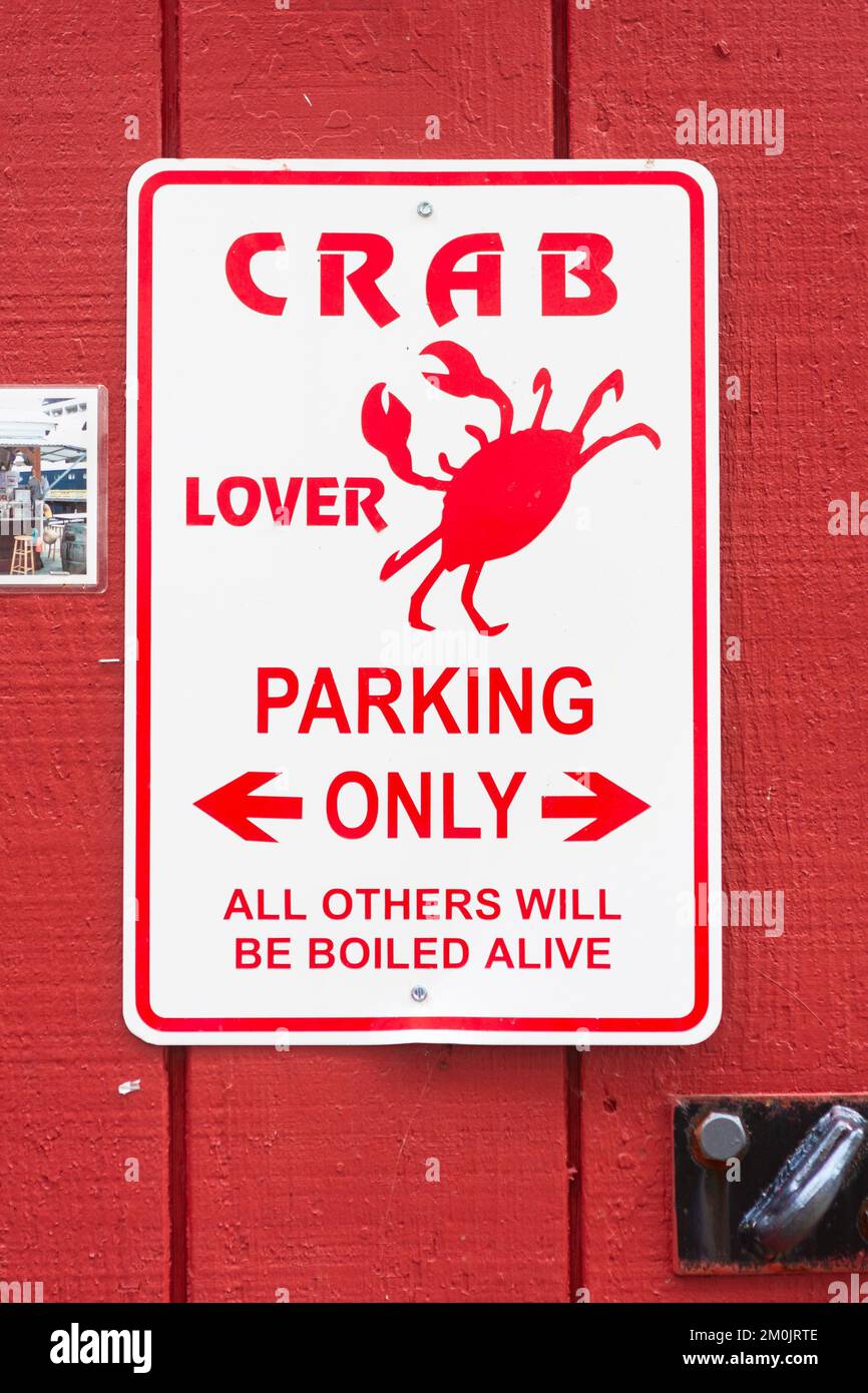 A funny crab sign printed in red on white hangs on a red wall in Juneau ...