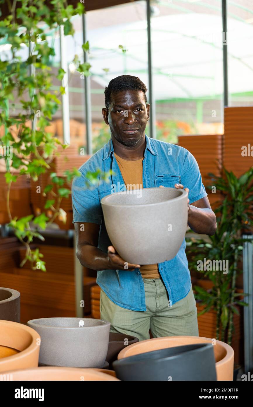 African american man chooses flower pots for indoor plants Stock Photo ...