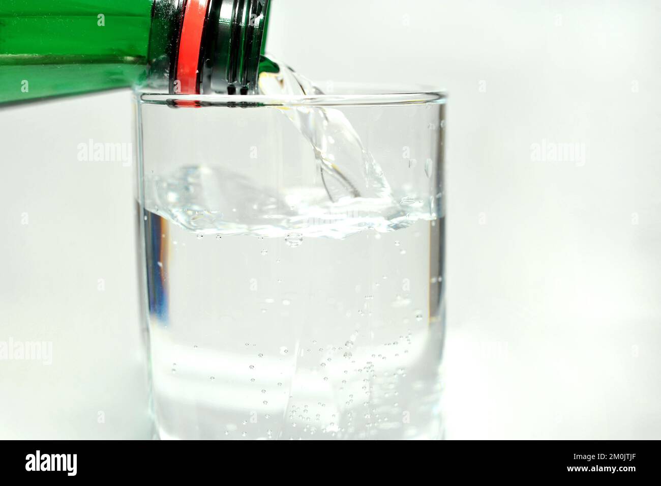 Pouring bottled mineral water for drinking into a glass on a white background Stock Photo - Alamy