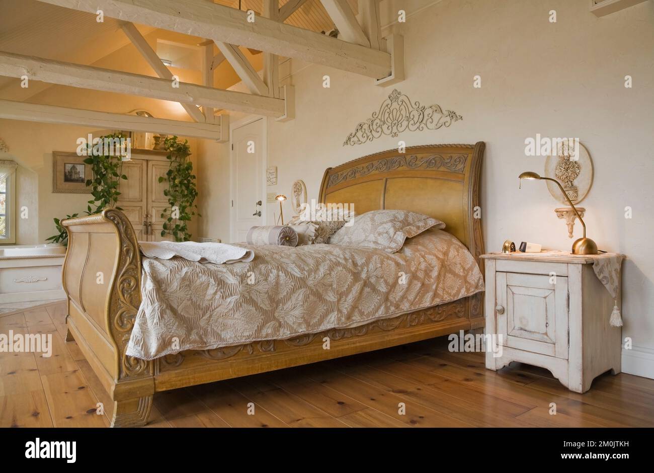 Luxurious antique wooden sleigh bed with bleached end table and ...