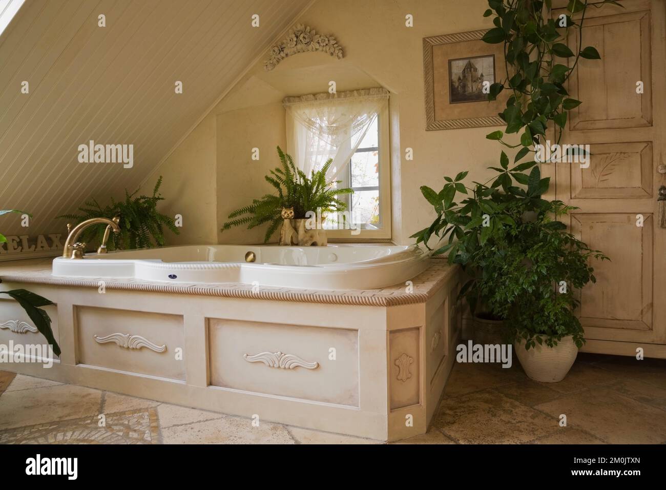 Whirlpool bathtub and bleached wooden armoire with green house plants ...