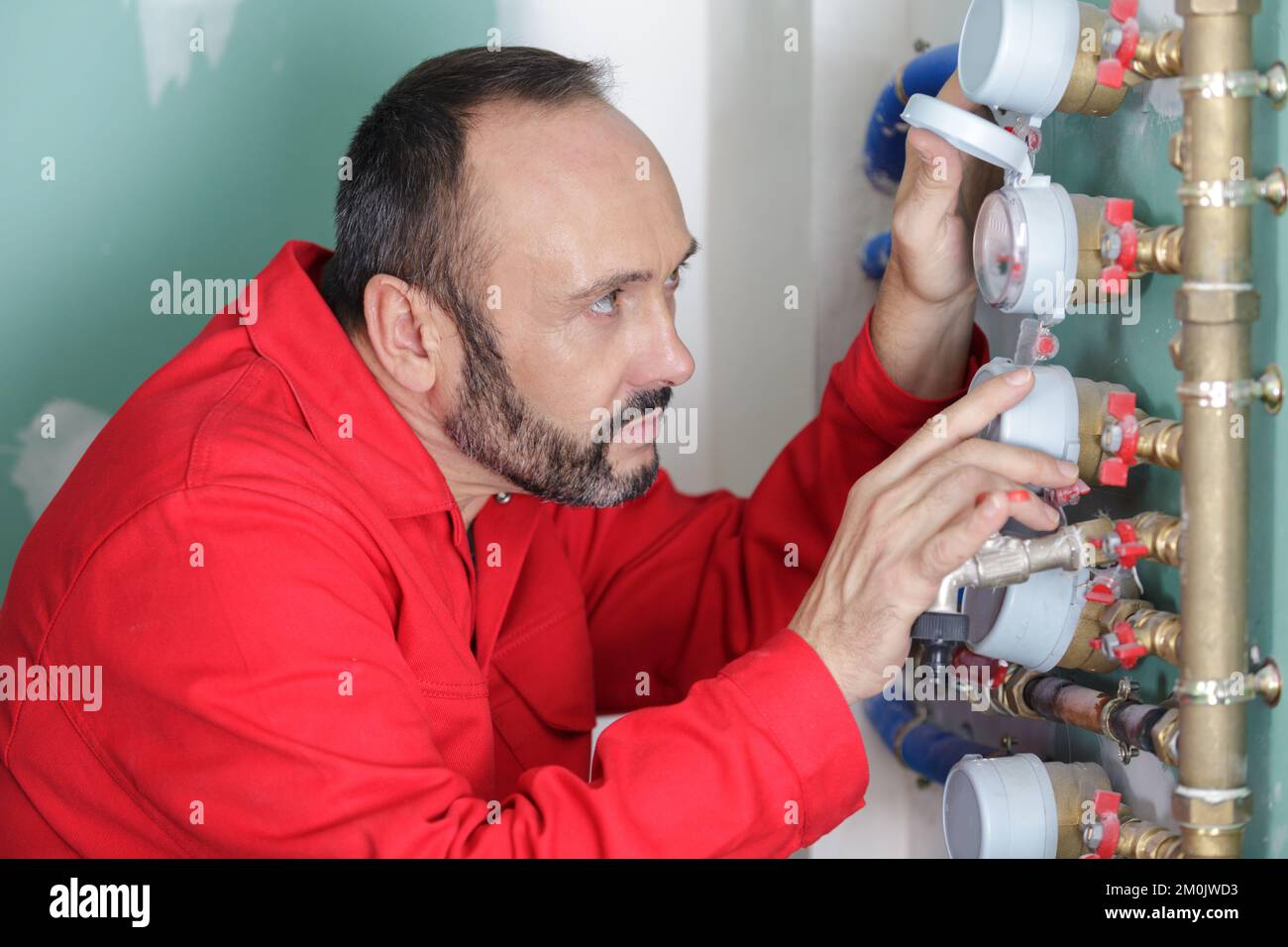 mature plumber looking at dial on pipework Stock Photo - Alamy