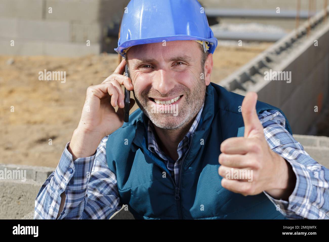 male builder on the telephone making thumbs-up gesture Stock Photo - Alamy