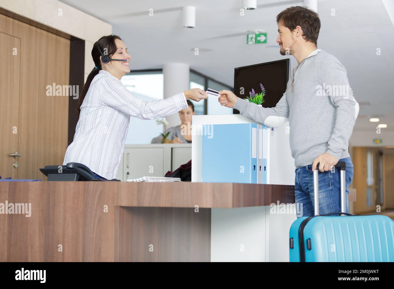 pretty hotel receptionist giving key to male guest Stock Photo - Alamy