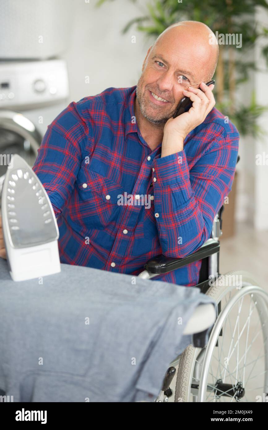 happy disabled man on the phone ironing clothing Stock Photo - Alamy