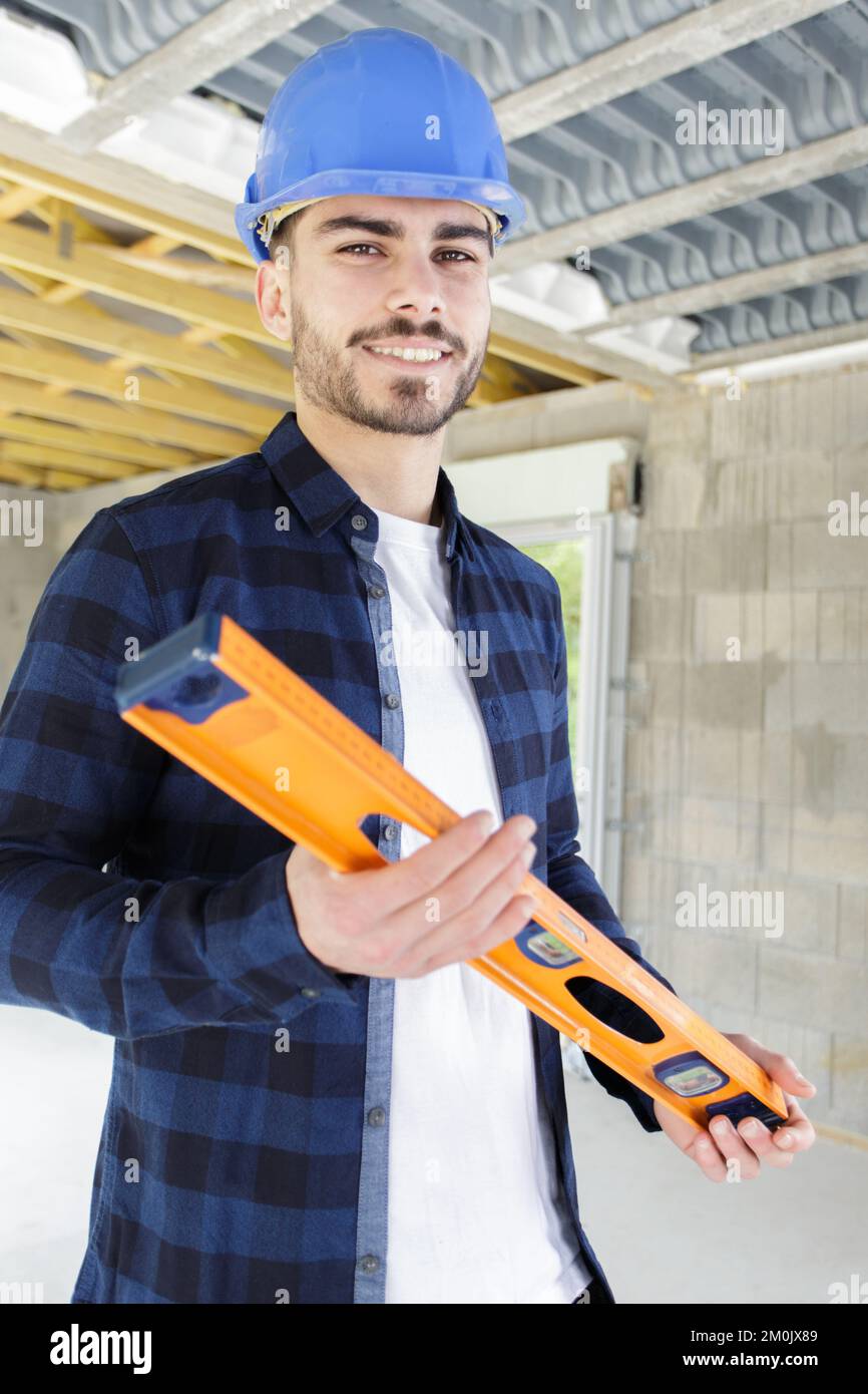portrait of young construction worker holding a spirit level Stock ...