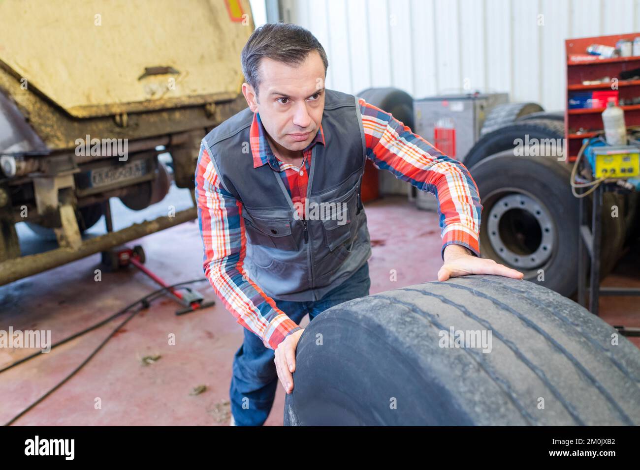 vulcanizing worker pushing heavy tire Stock Photo - Alamy