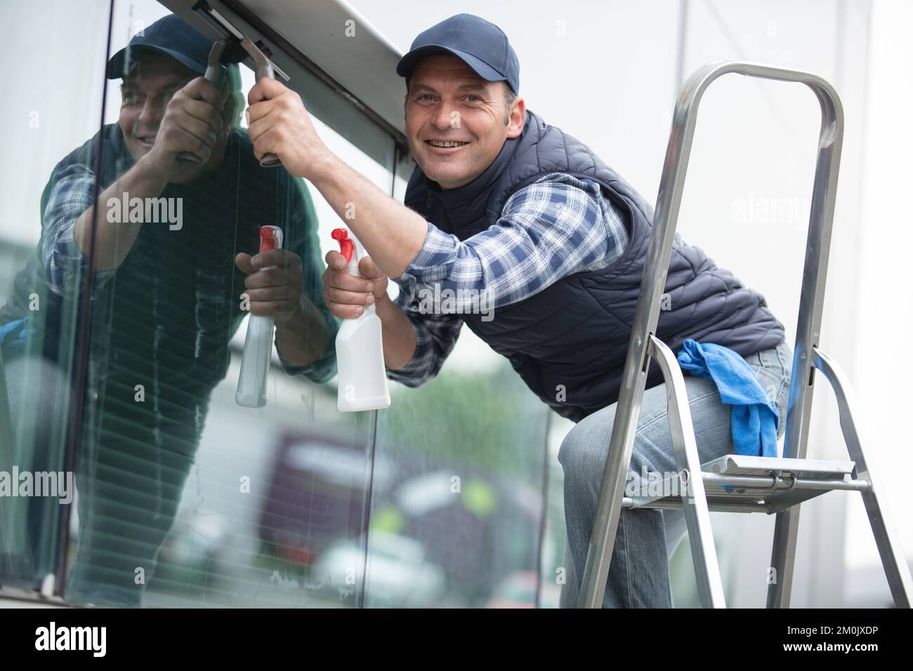 happy man on ladder caulking outside window Stock Photo - Alamy