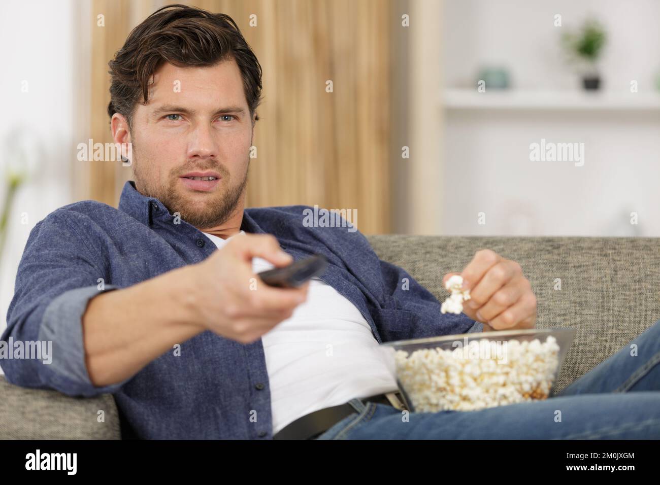 man with tv remote control and popcorn Stock Photo - Alamy