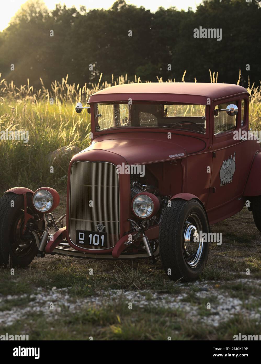 A beautiful red Ford Model A car parked in the wilderness, surrounded ...