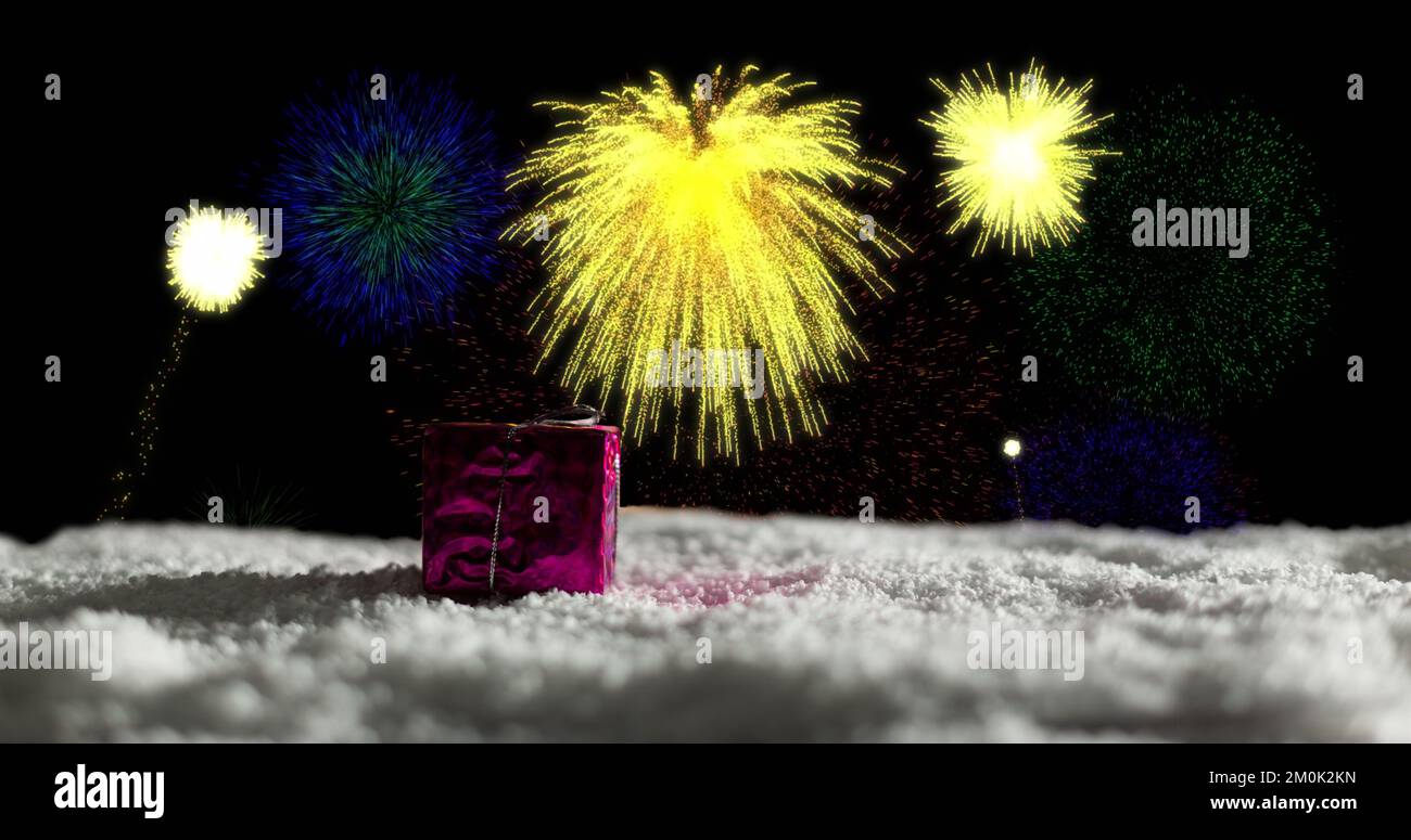 Image of christmas present in snow and yellow fireworks exploding in ...