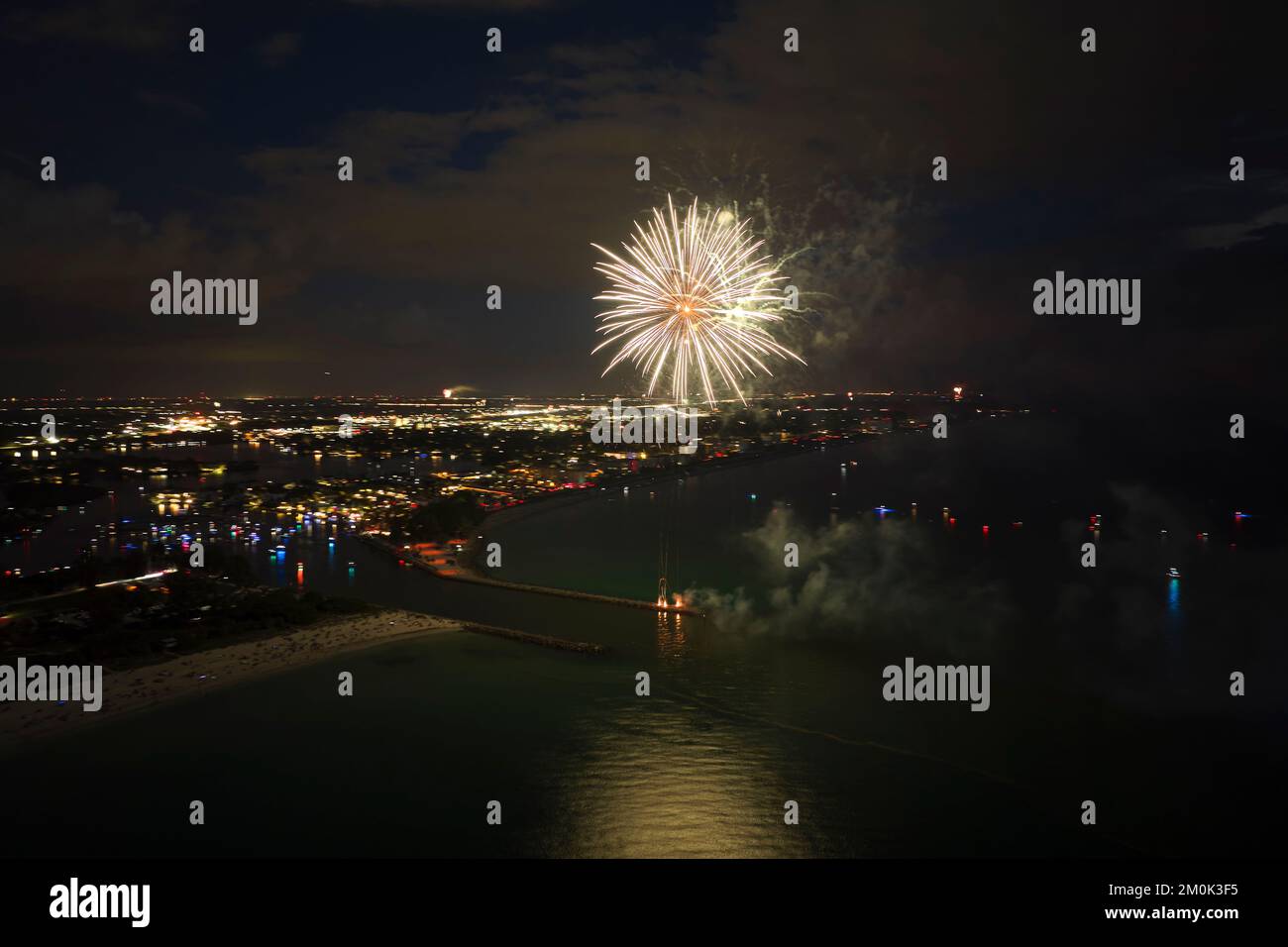 Aerial view of bright fireworks exploding with colorful lights over sea ...