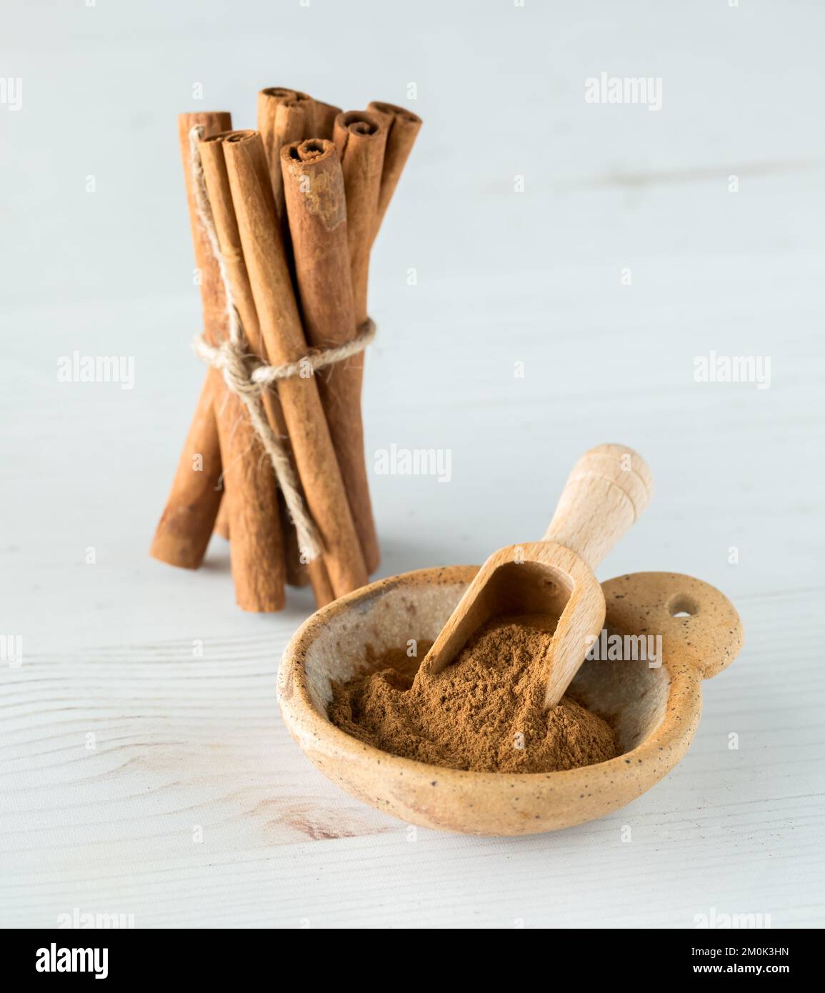 A small dish of cinnamon powder with a bunch of sticks in behind Stock ...