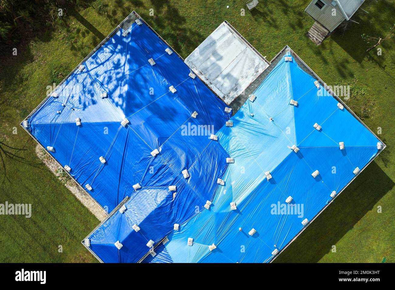 Aerial view of damaged in hurricane Ian house roof covered with blue ...