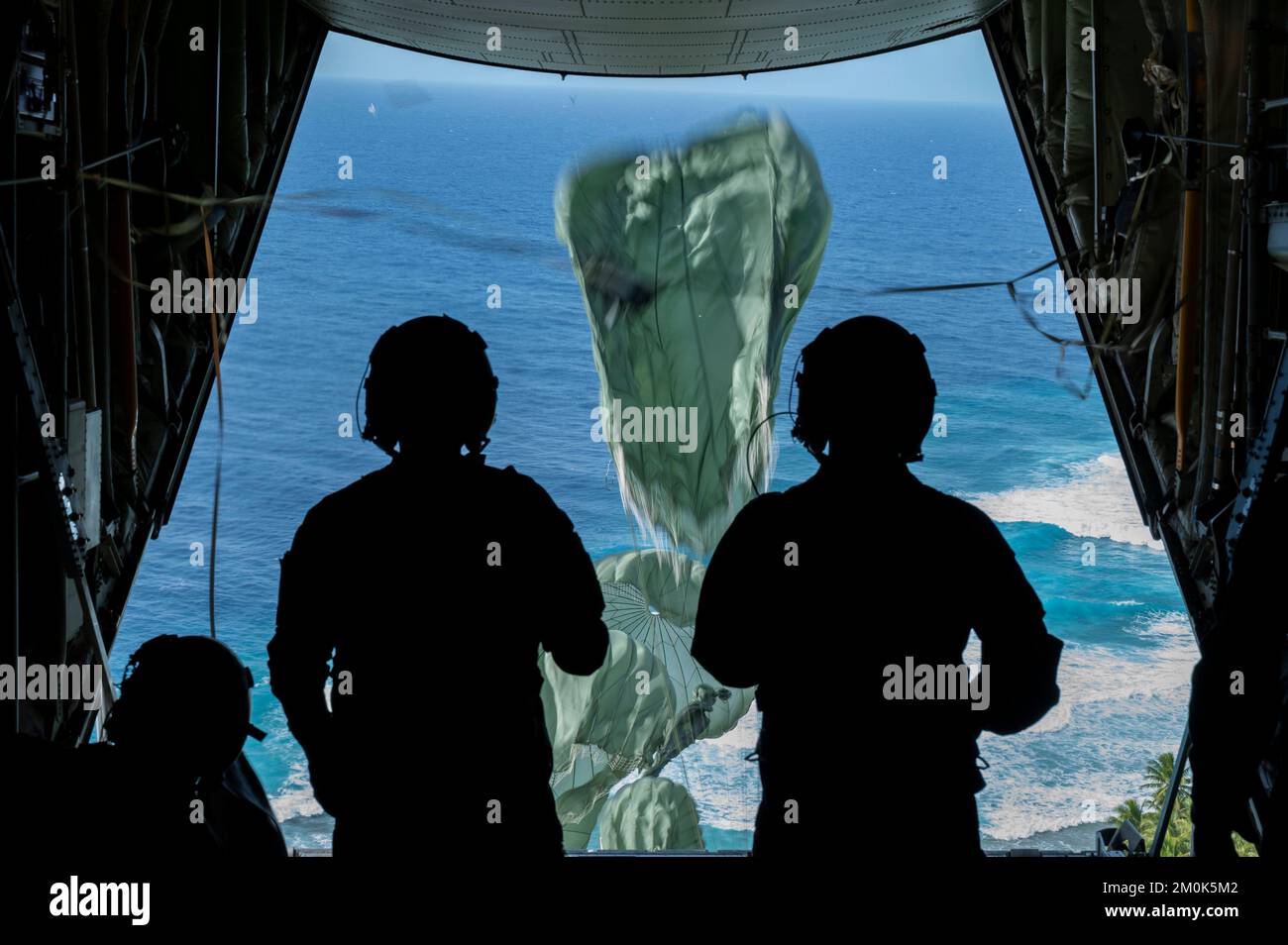 U.S. Air Force loadmasters watch as parachutes open on supply crates ...