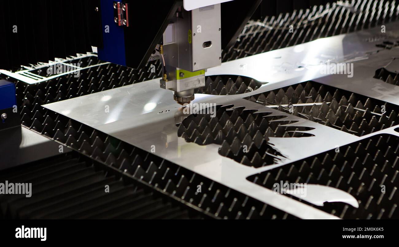 CNC laser cutting machine cutting metal sheet in factory. Industrial ...