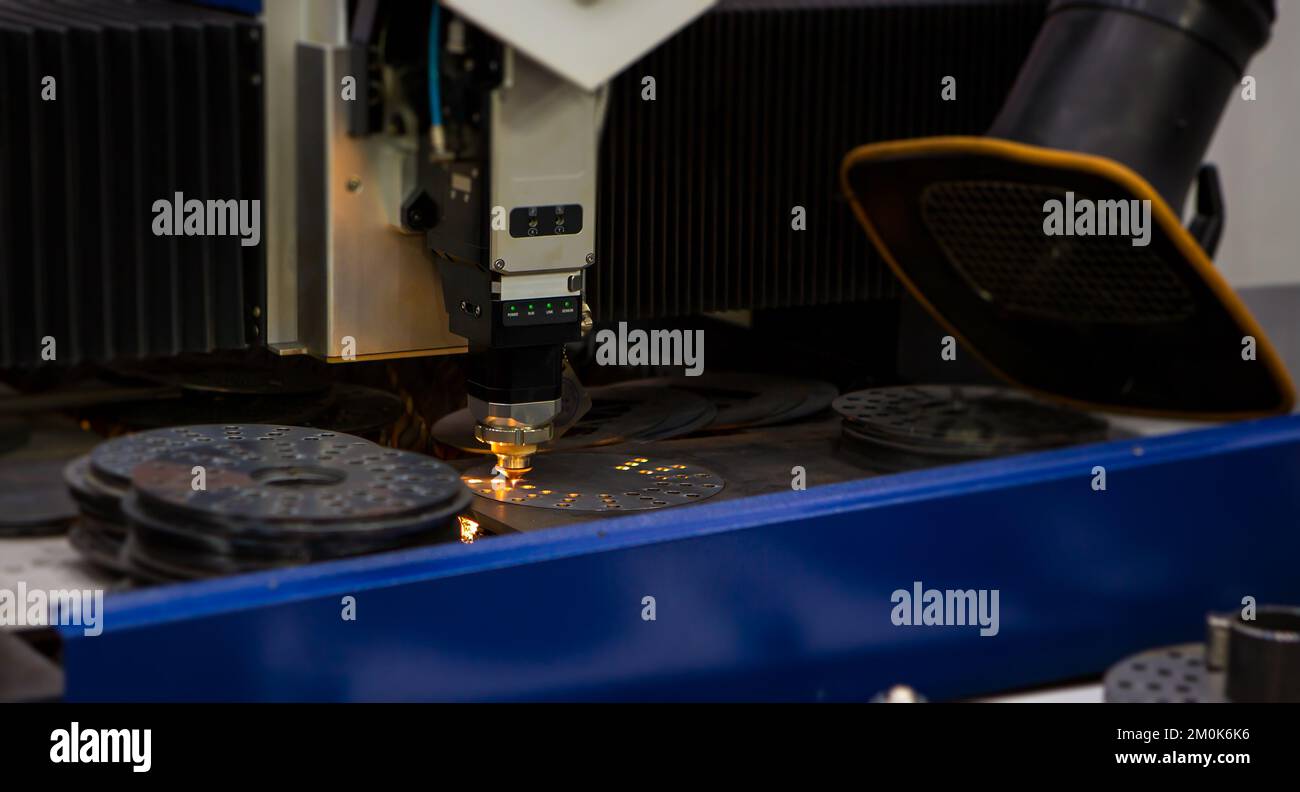 CNC laser cutting machine cutting holes on metal workpiece in factory ...