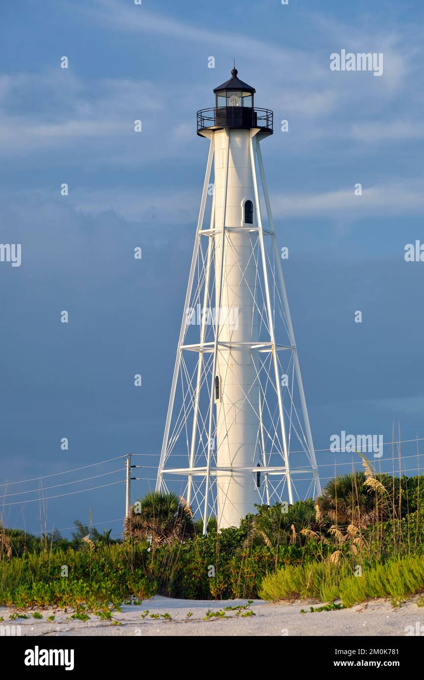 White tall lighthouse on sea shore against blue sky for commercial ...