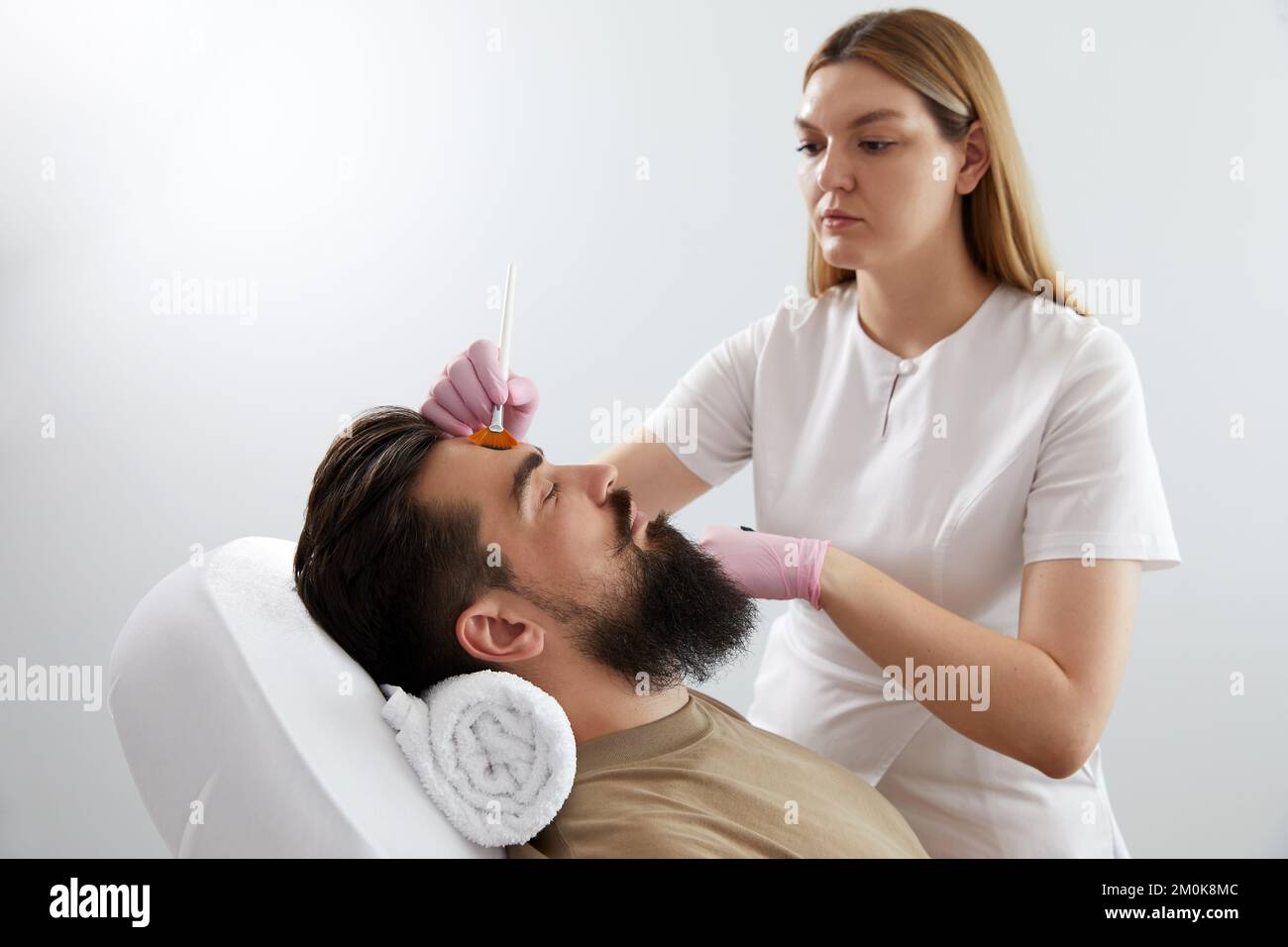 Cosmetologist applying a clay mask to male face. Spa treatment and face ...