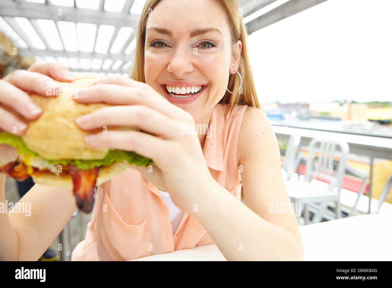 This looks delicious. Portrait of a pretty young woman eating a massive ...