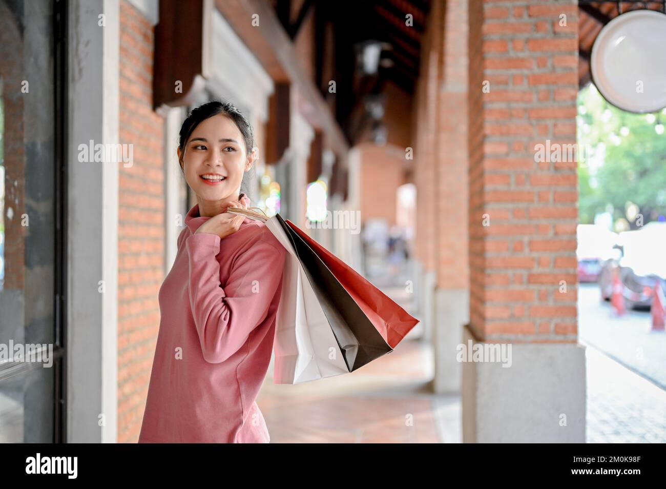 Confident young Asian woman in casual clothes carrying her shopping ...