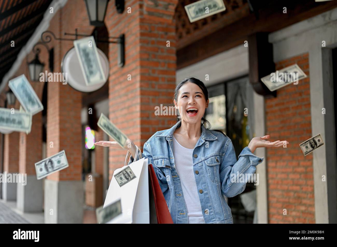 Overjoyed and carefree young Asian female shopper screaming with joyful ...