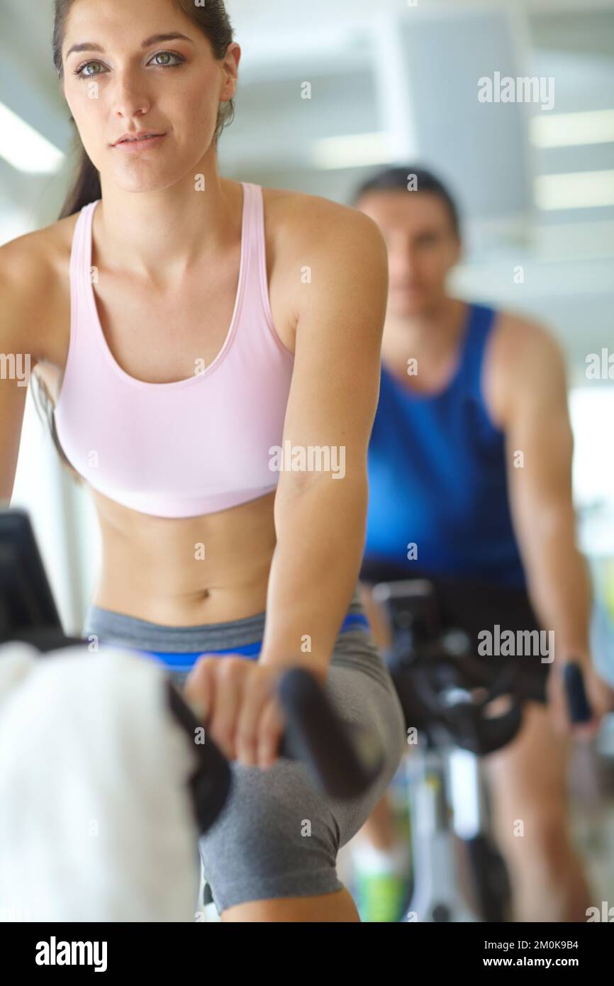 Filled with vitality. A man and woman exercising in spinning class at ...