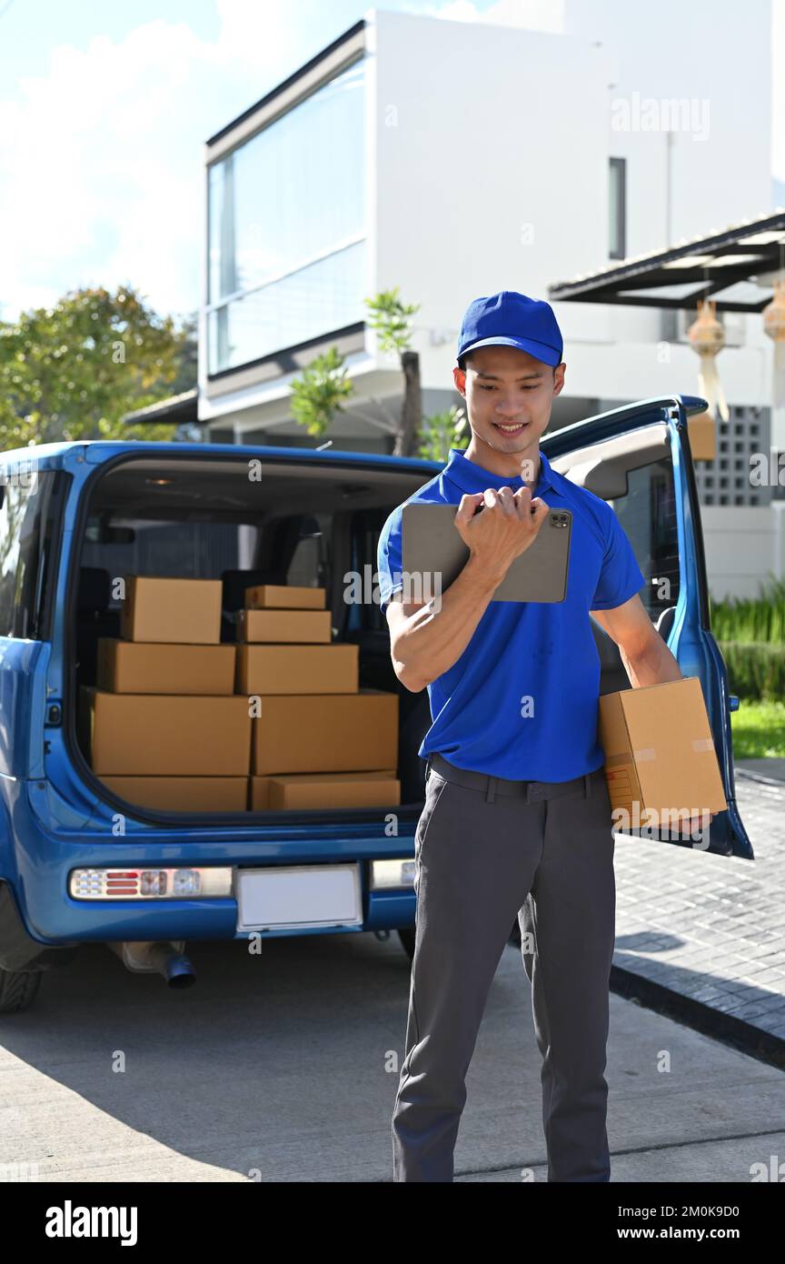 Young Asian delivery man checking orders with tablet before handing ...