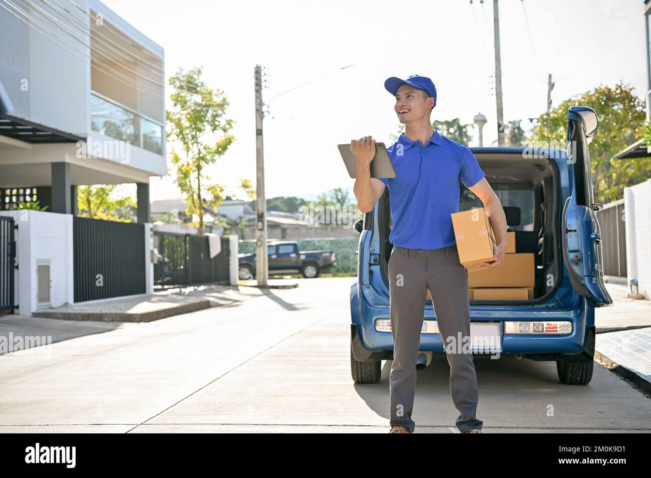 Professional delivery man in blue uniforms standing in front of his van ...