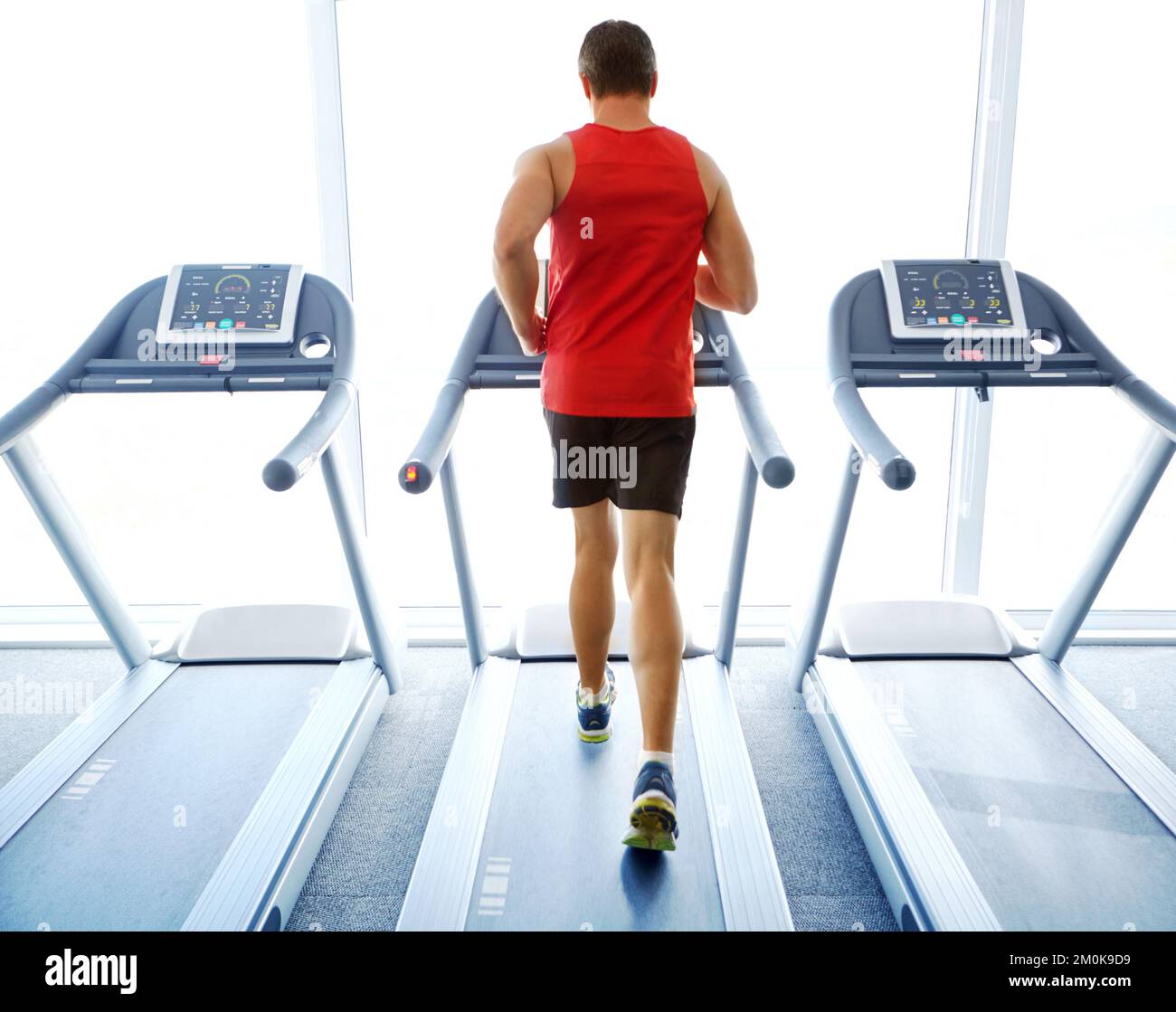 Keeping a steady pace. A handsome young man exercising on a treadmill ...