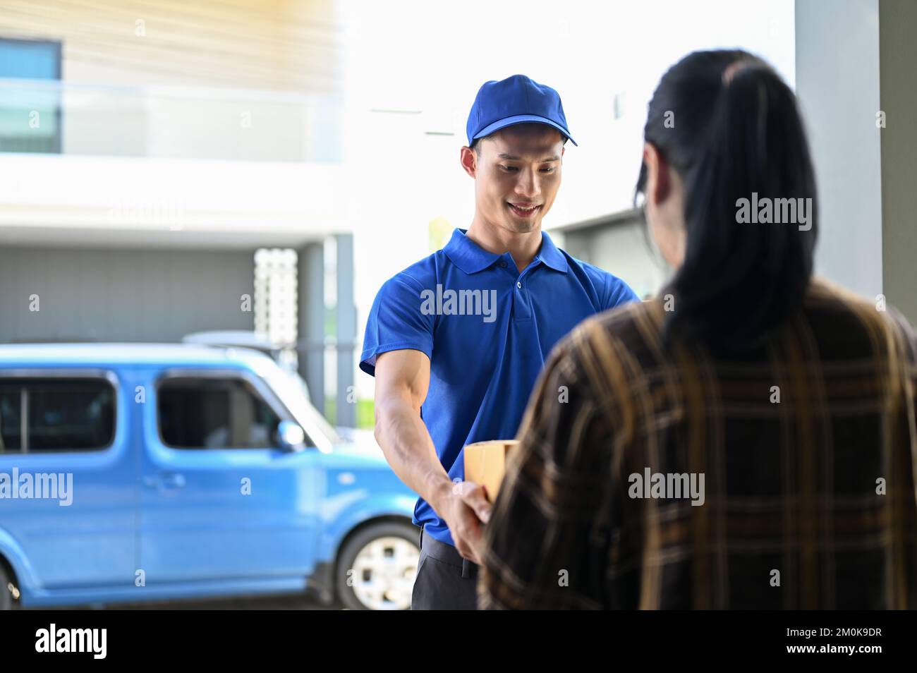Professional delivery man in blue uniforms handing the package to ...