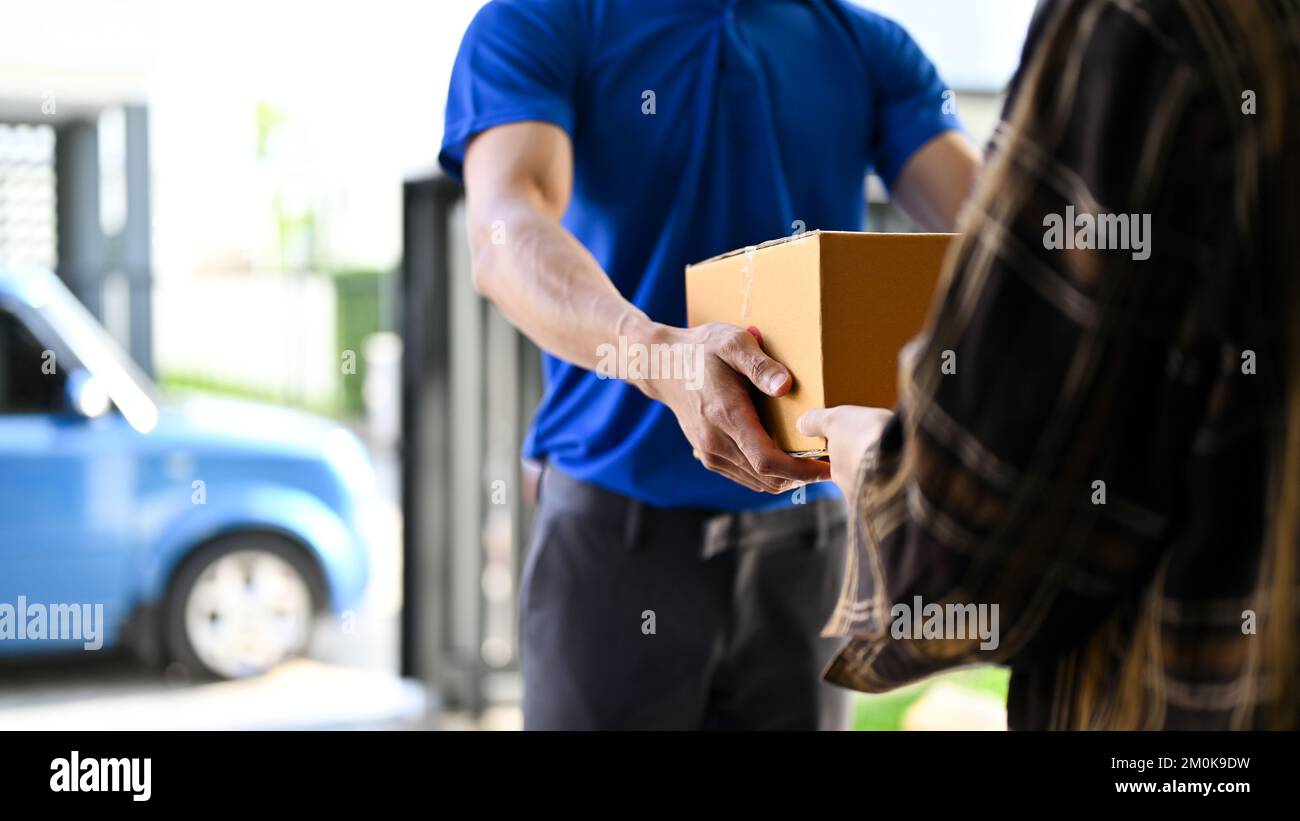 Close up view of delivery man in blue uniforms handing the parcel to ...