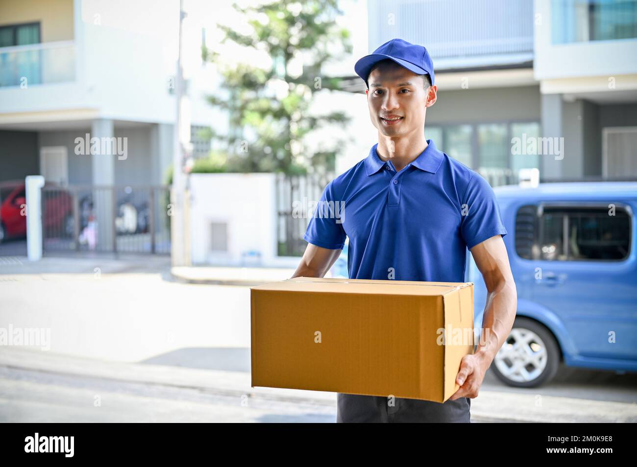Professional delivery man in blue uniforms holding the package for ...