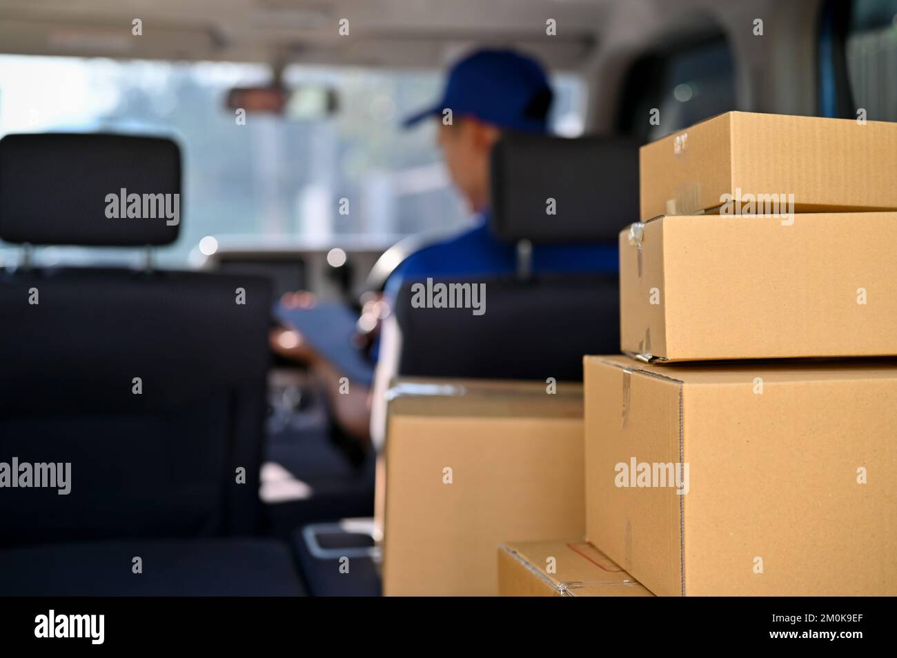 Parcel boxes in the delivery van with delivery man in the front seat as ...