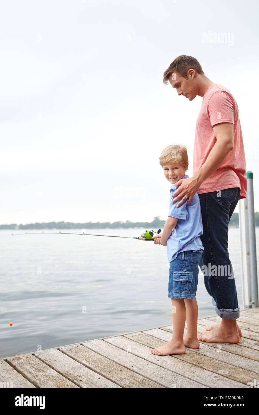 Learning how to fish by the master. A father teaching his son how to ...