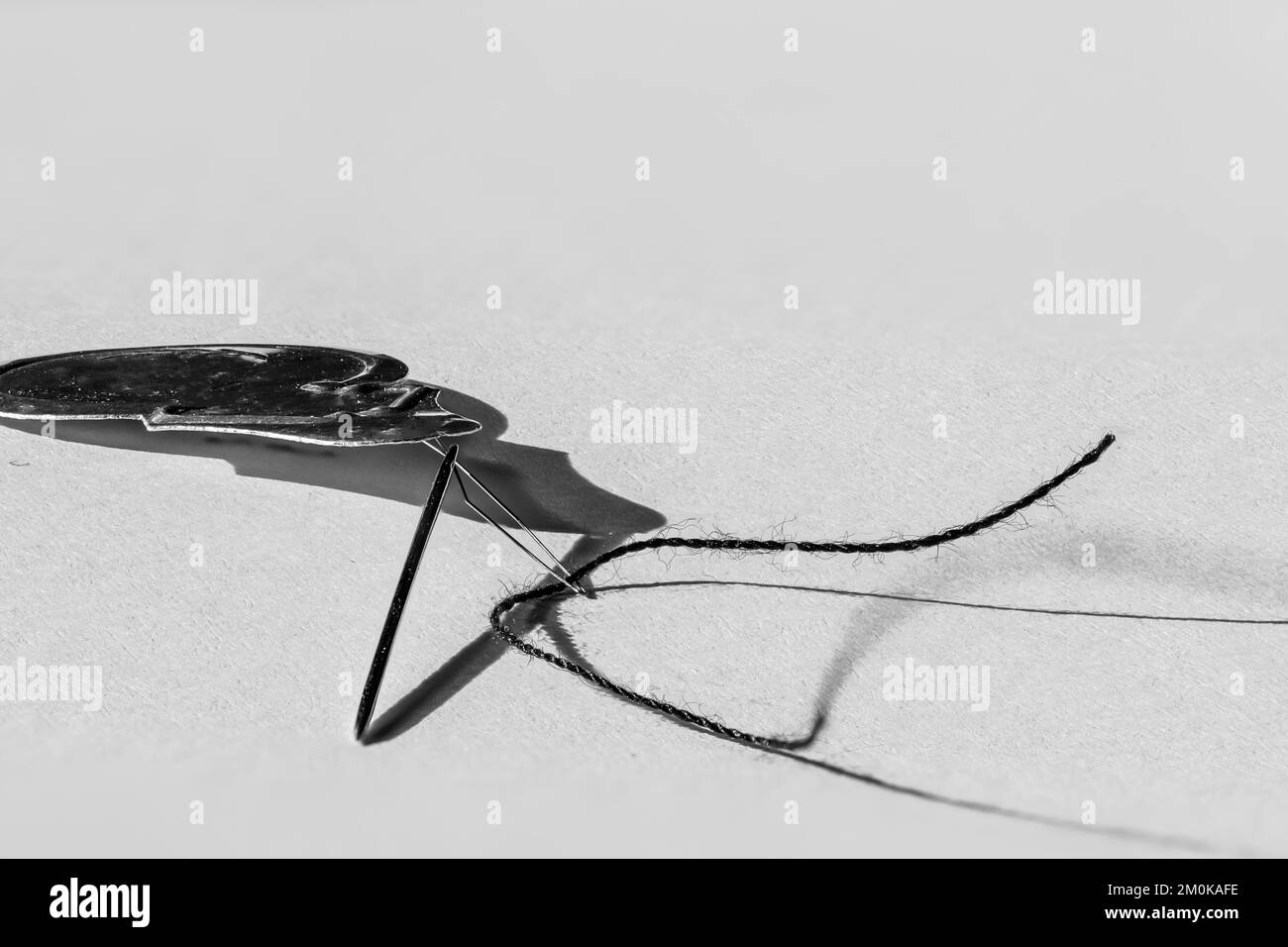 Sewing needle threader tool in use and a single black string Stock ...