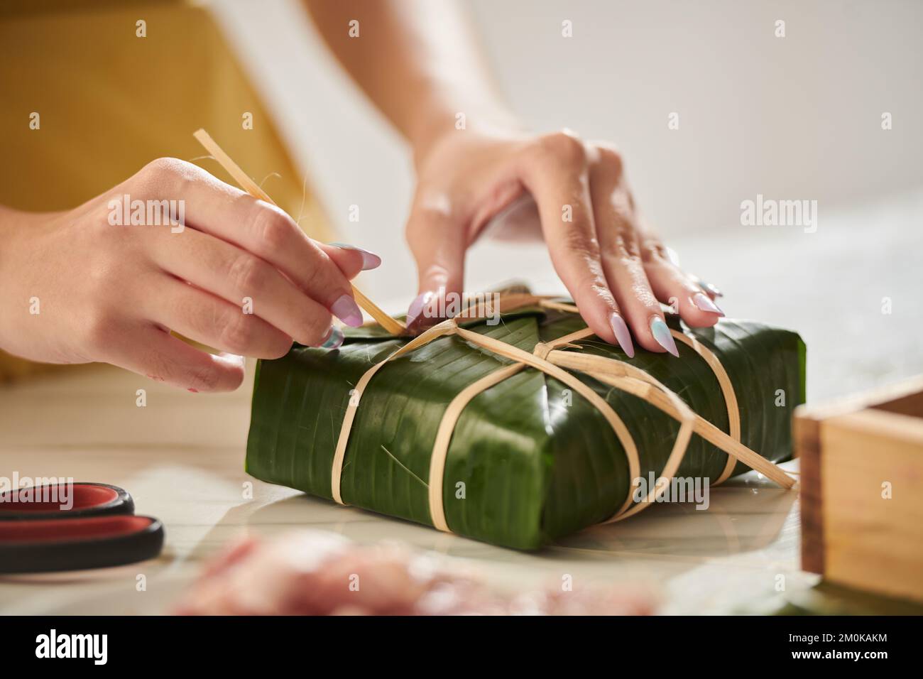 Hands of woman packing rice cake in banana leaves for spring festival ...
