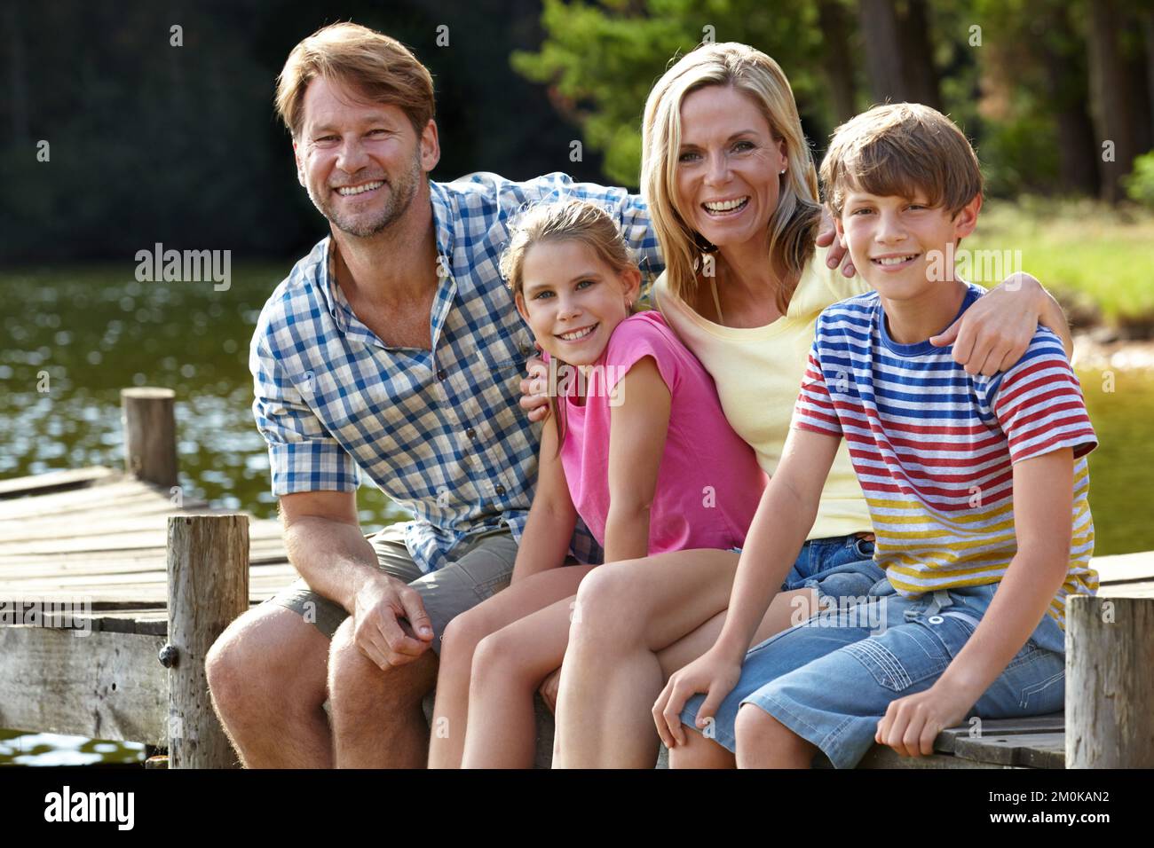 Family laughter. Portrait of a loving family sitting on a pier out on a ...