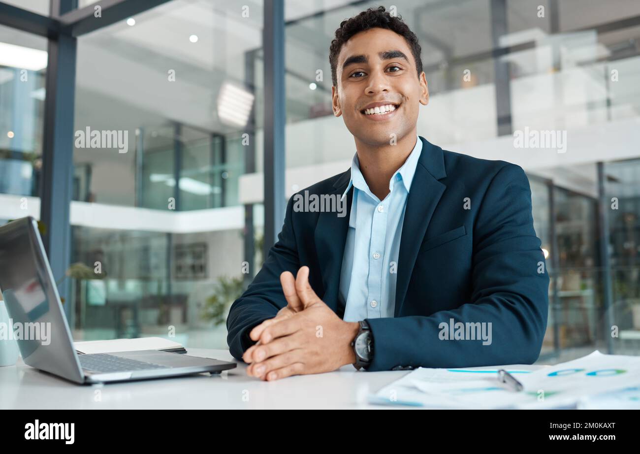 Portrait of a happy mixed race businessman smiling while working on a ...