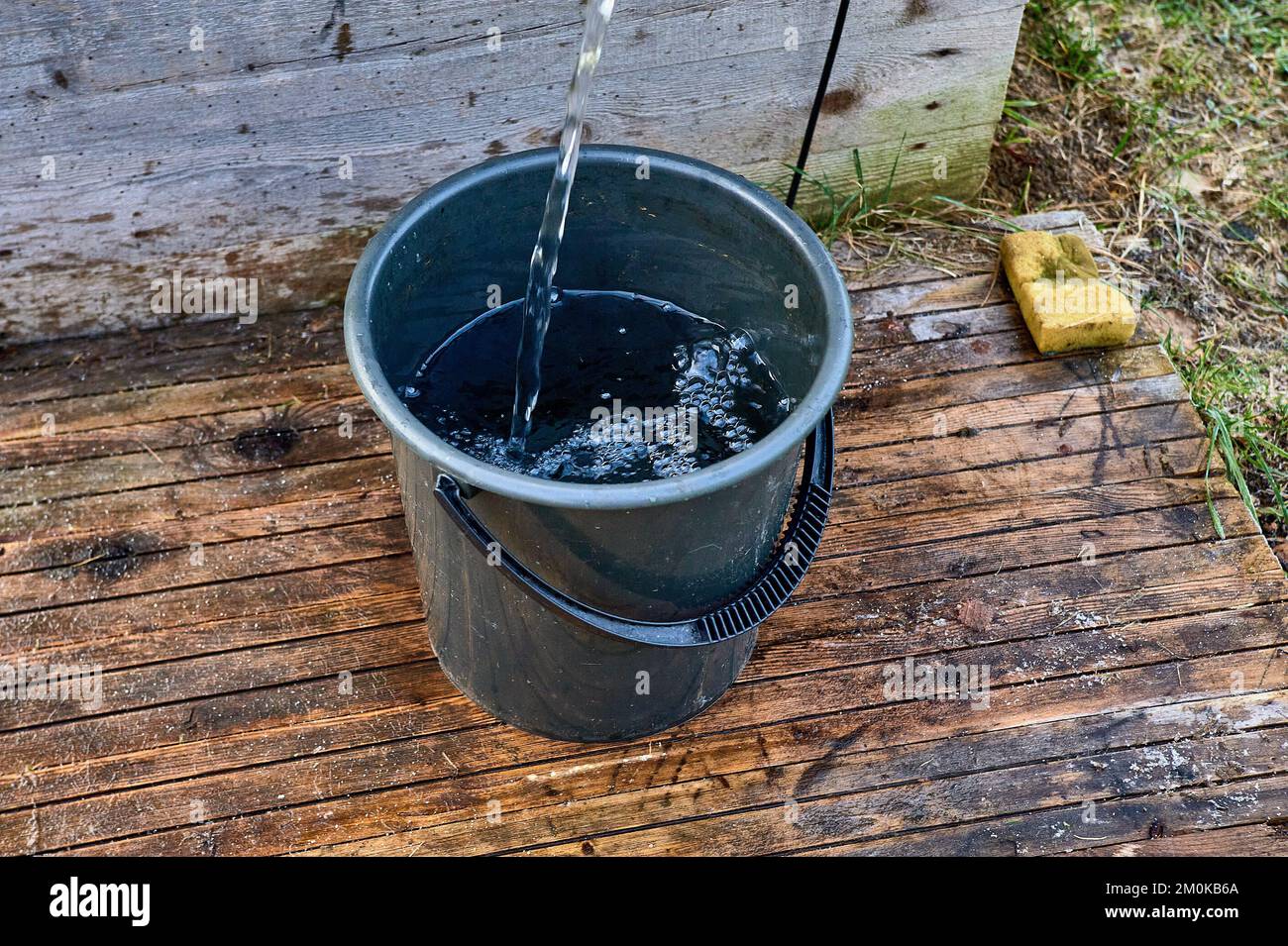 a black plastic bucket is filled with water from the pump Stock Photo ...