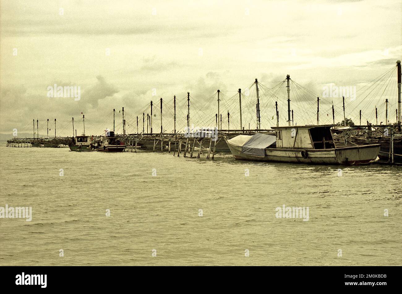 Boats and a line of sailing bagans (bagang perahu) on the coastal water ...