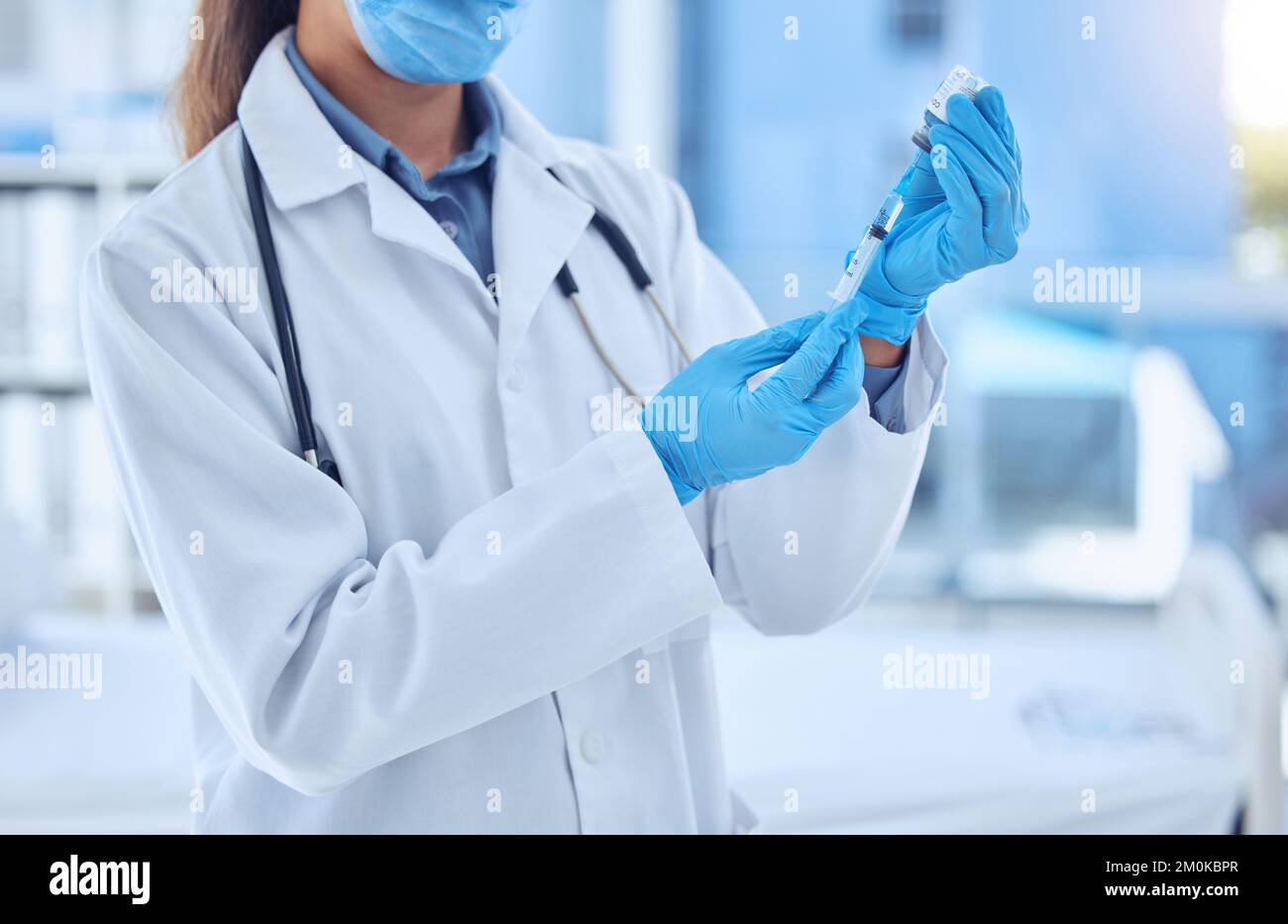a female doctor preparing a dose of medication in a syringe while ...