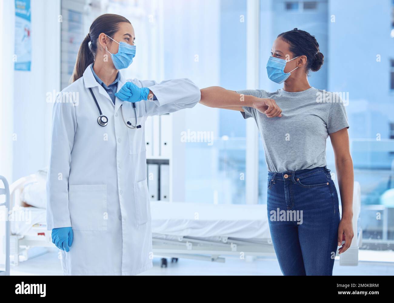 Doctor greeting patient with an elbow bump. Mixed race doctor giving a ...
