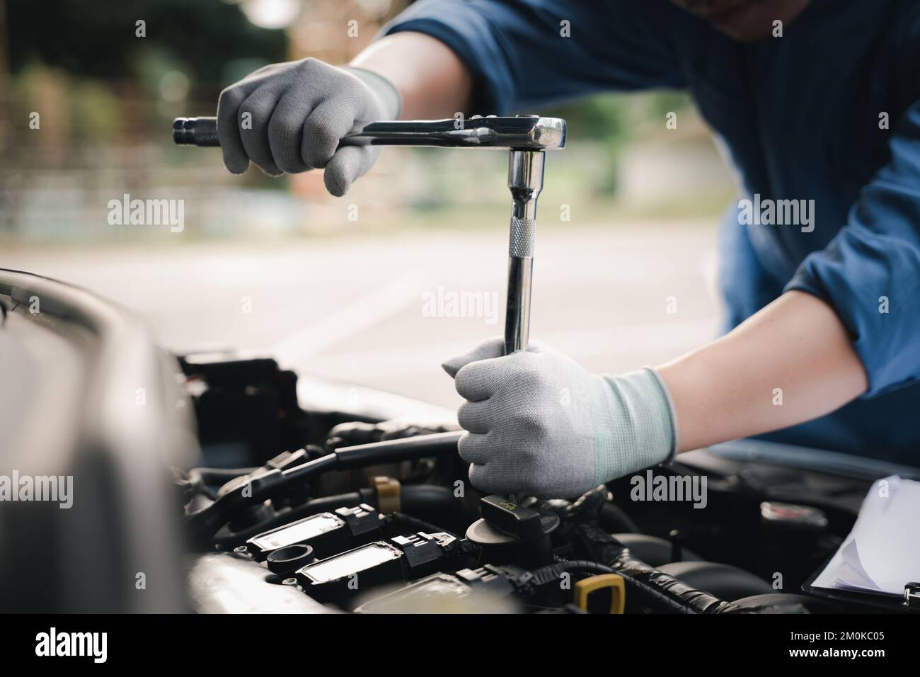 Asian auto mechanic man working on car engine using wrench to repair ...