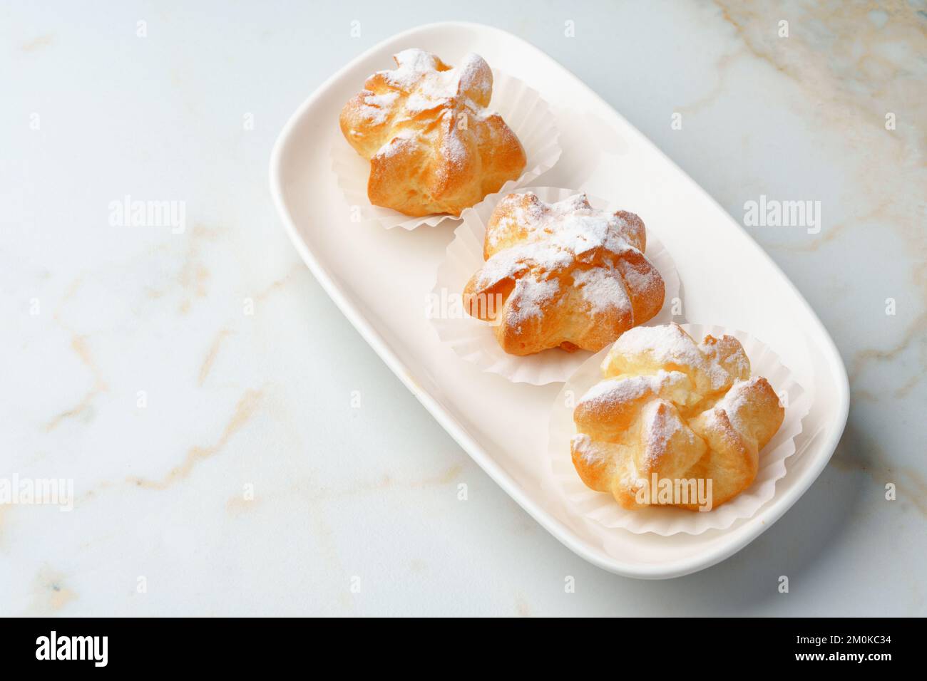 Homemade profiteroles with powdered sugar on white plate Stock Photo ...