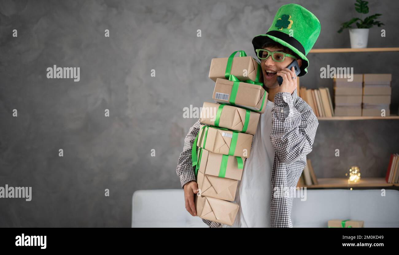 Happy handsome guy in leprechaun hat holding bunch of gifts on St ...