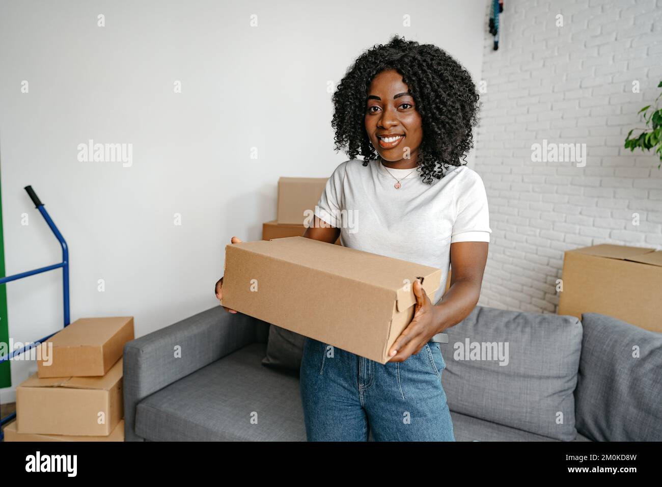 Happy african young woman with many cardboard boxes at home Stock Photo ...