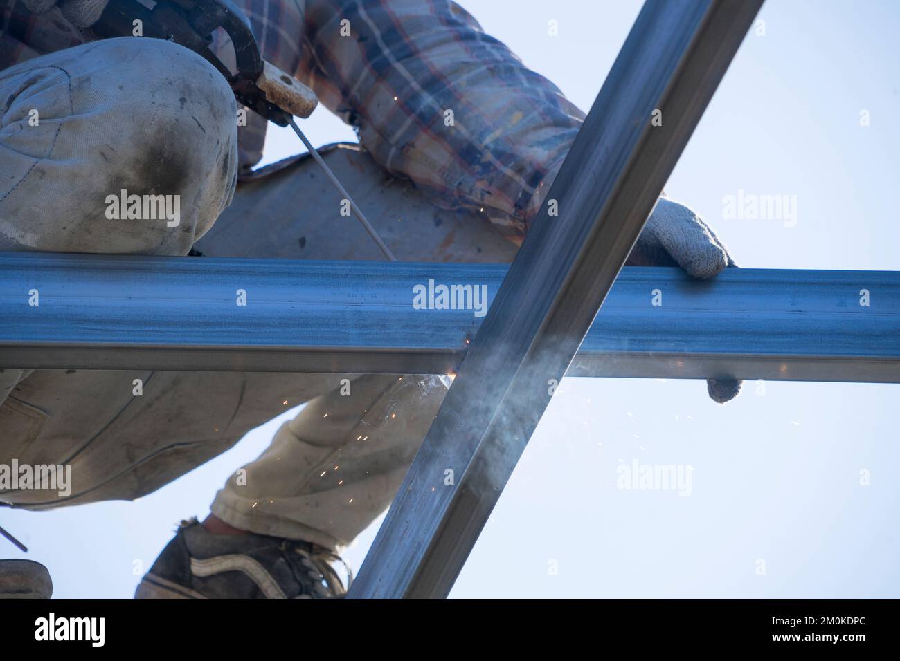 Asian male welder is welding steel beams in process of home renovation ...