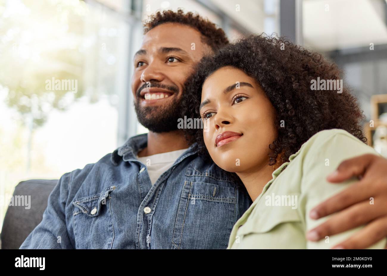 Young Mixed Race Couple Embracing While Watching Tv On The Couch At